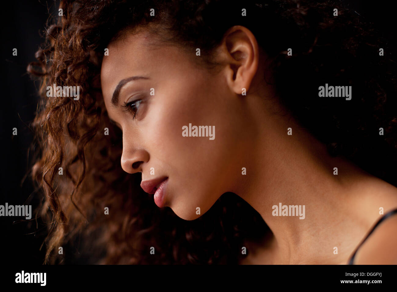 Young woman in profile against black background Stock Photo - Alamy