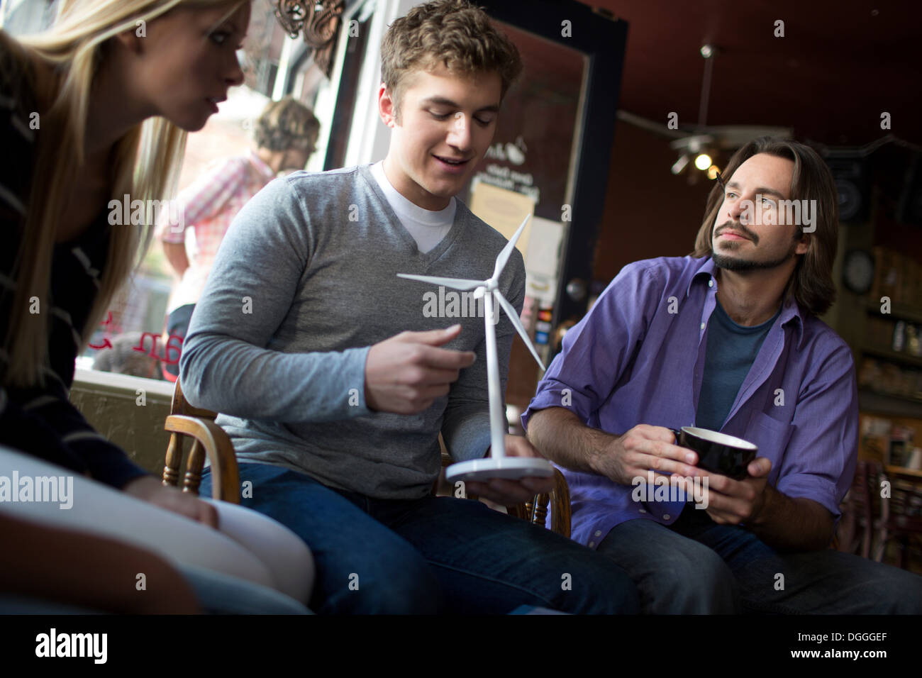 Small study group looking at model in coffee house Stock Photo - Alamy