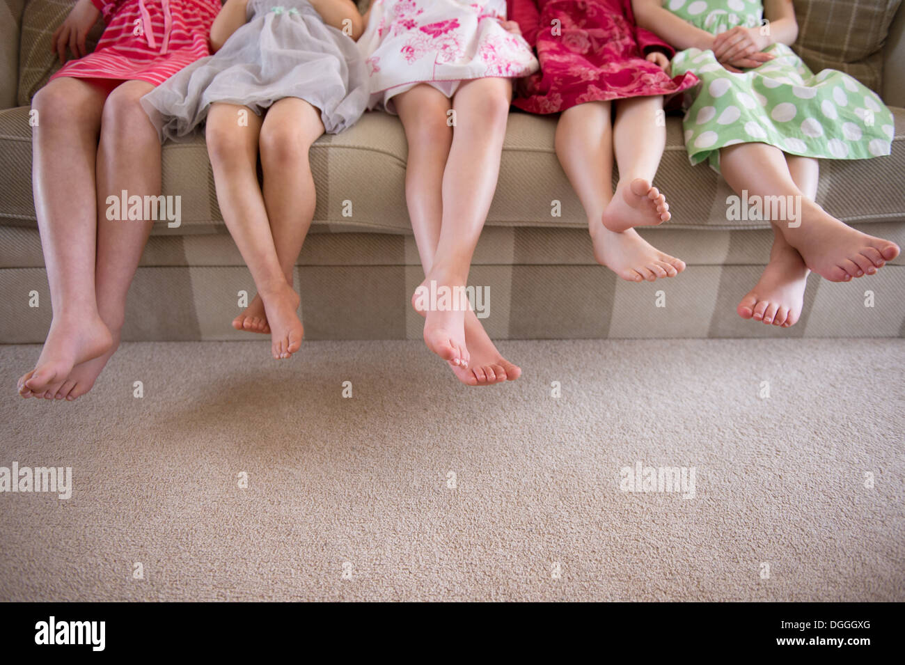 Girls sitting together in a row on sofa Stock Photo - Alamy