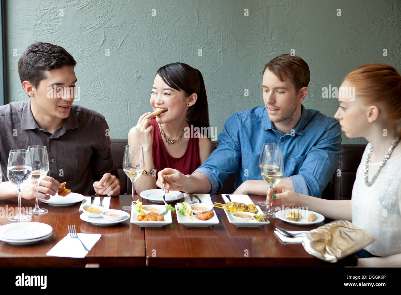 Four friends eating food in restaurant Stock Photo - Alamy