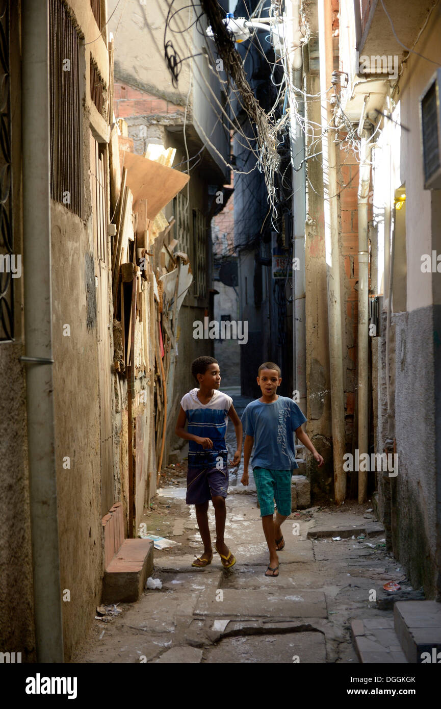 Two boys in a narrow alley in a slum or favela, Jacarezinho favela, Rio ...