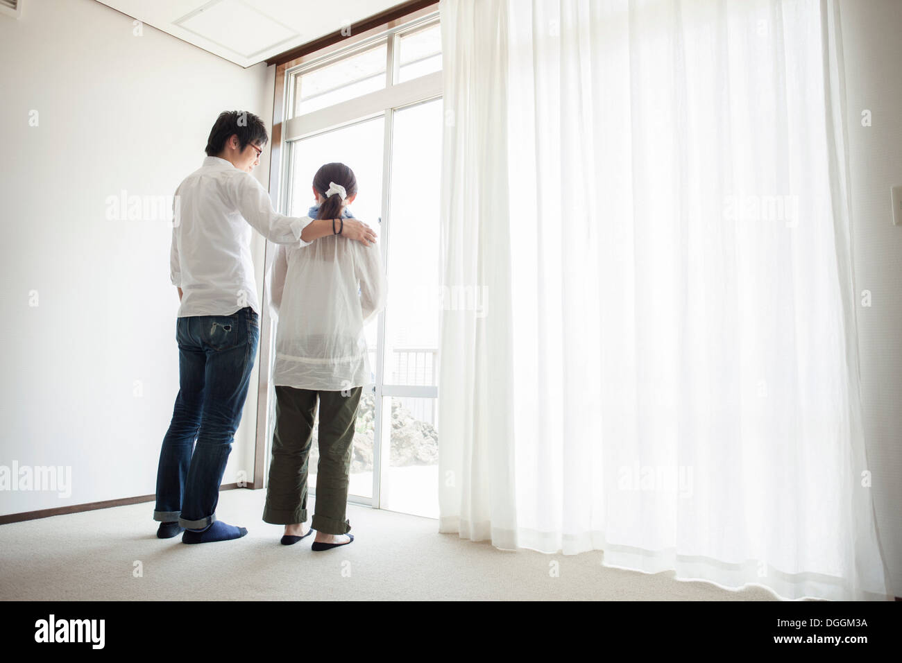 Couple standing by window Stock Photo - Alamy