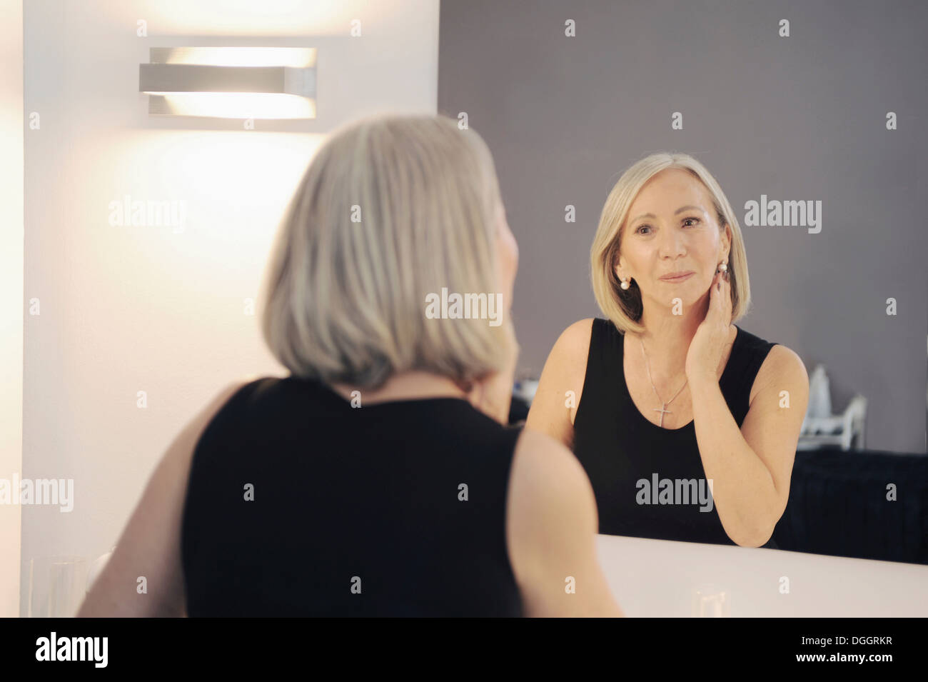 Senior woman looking at reflection in mirror Stock Photo - Alamy