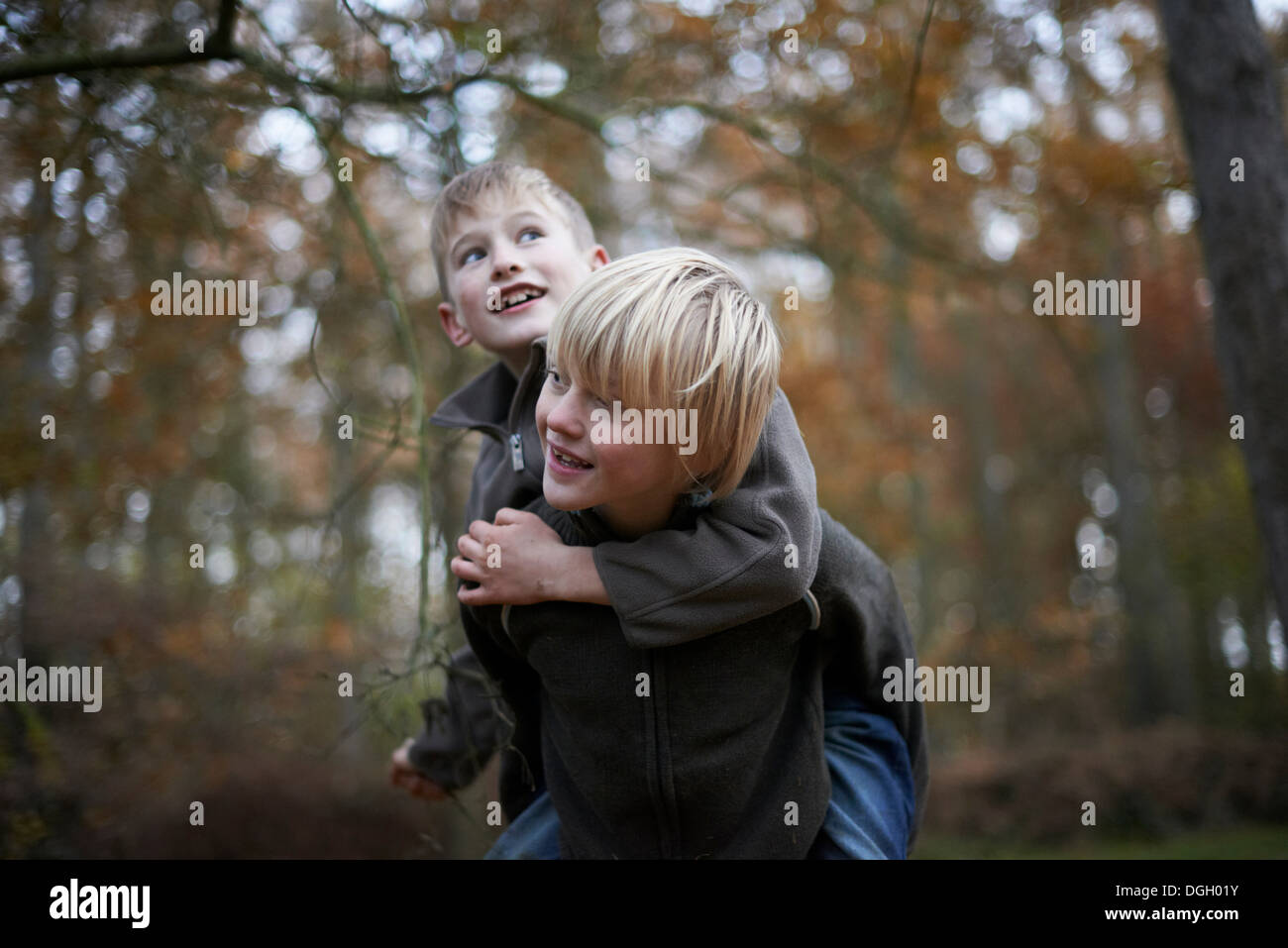 Boy giving friend a piggyback through forest Stock Photo - Alamy