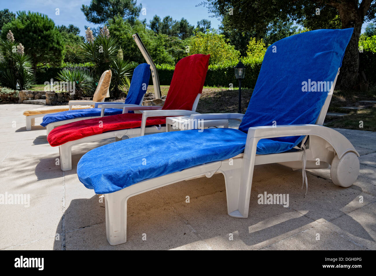 Plastic recliner chairs covered with bright blue or red fabric on a ...