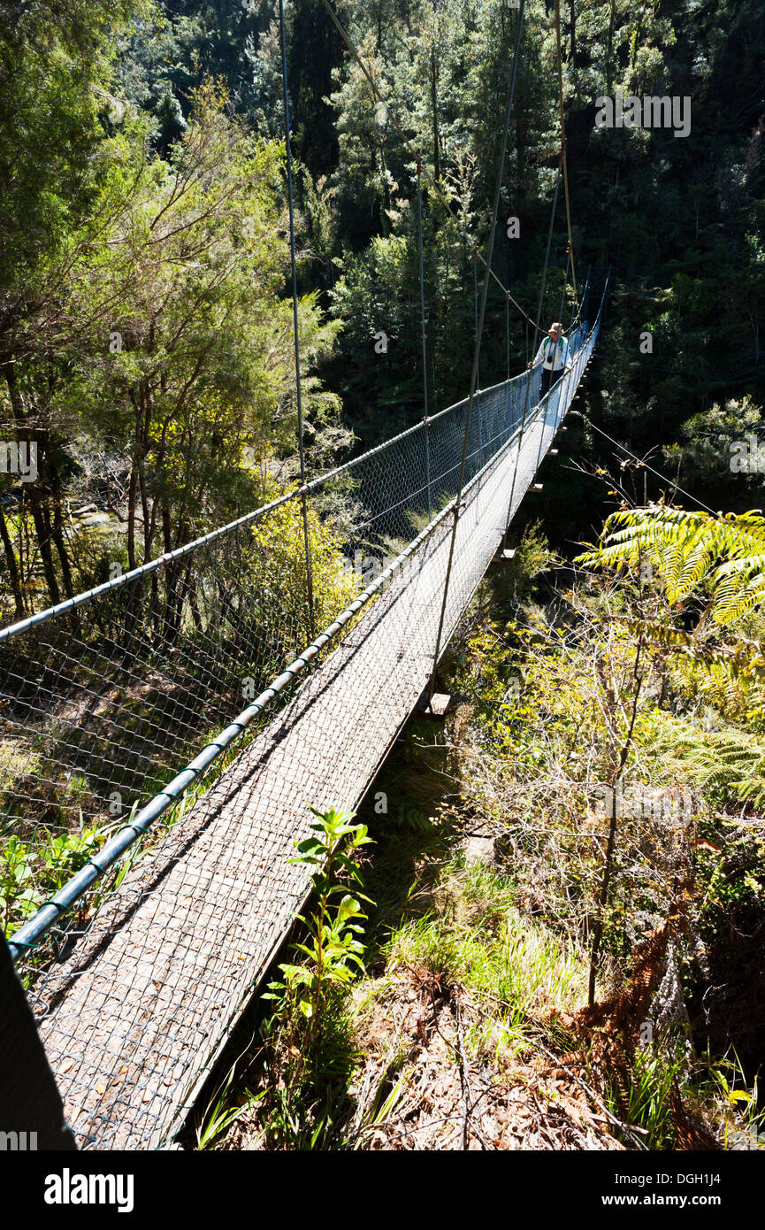 A walker crossing a suspension footbridge over a river on the Abel ...