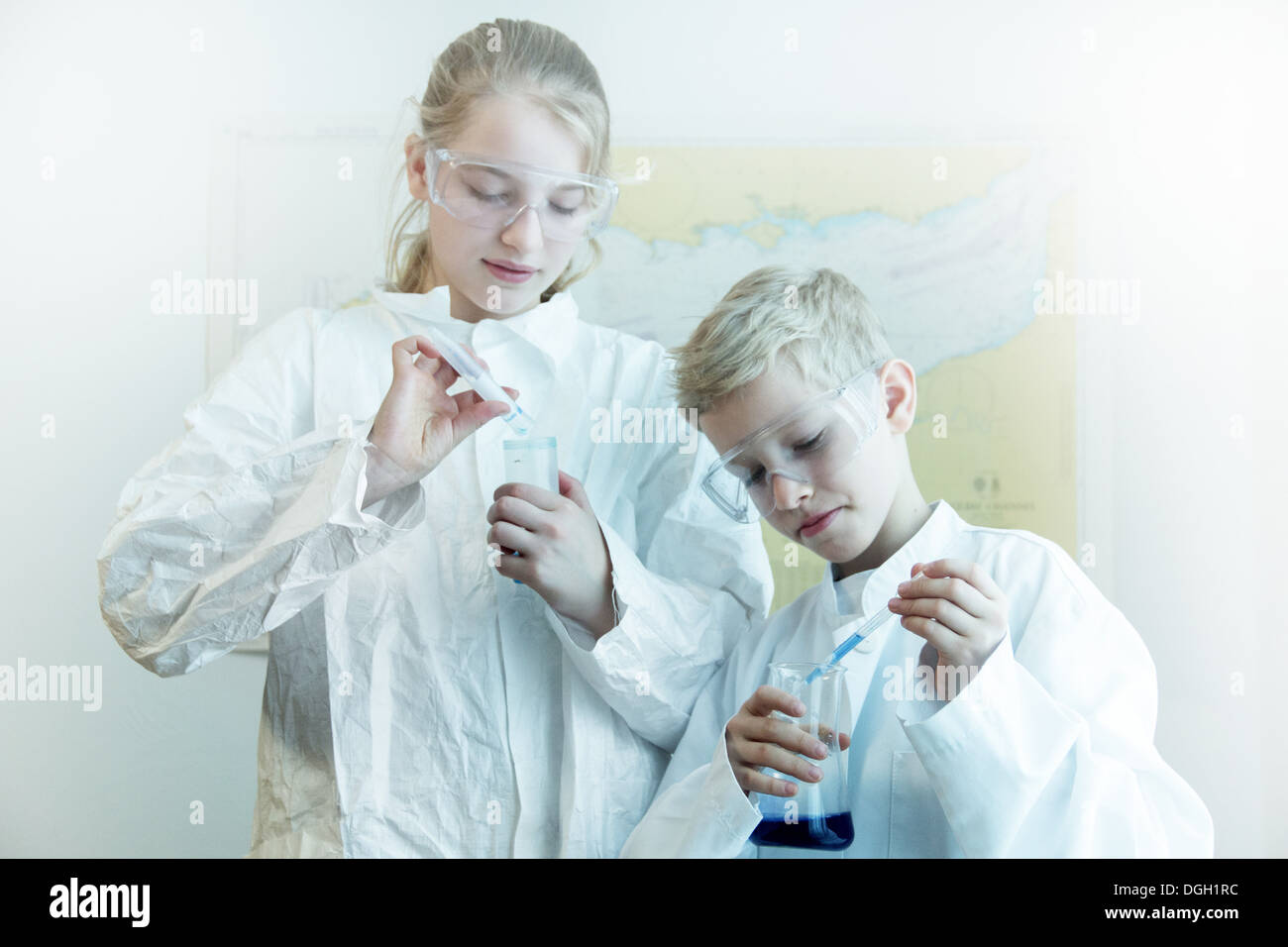 Brother and sister wearing safety goggles doing science experiment ...
