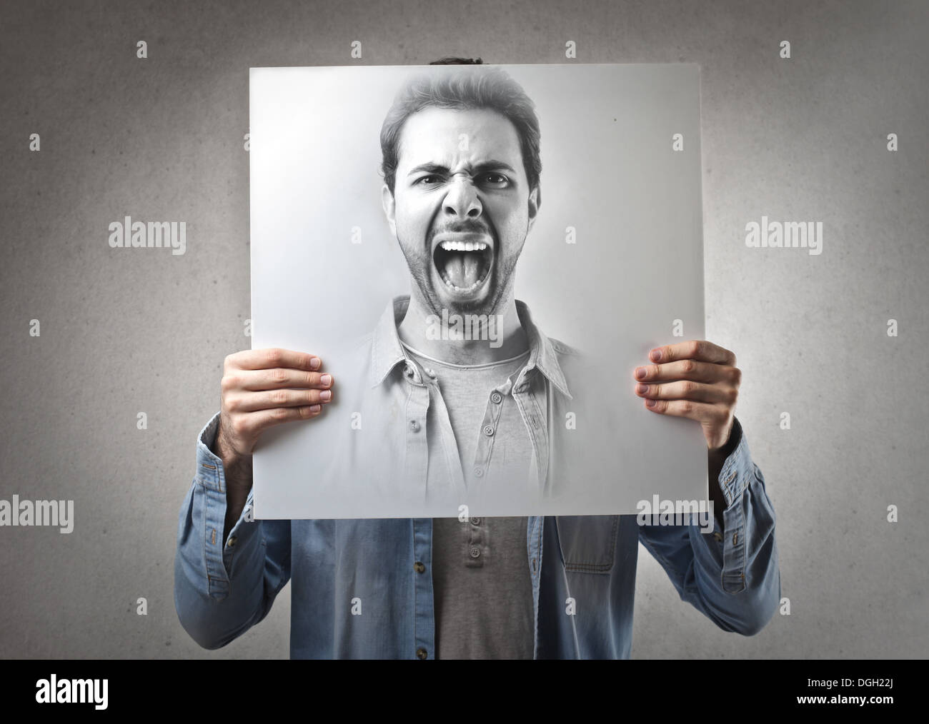 Man covering his face with a cardboard on which is drawn is face ...