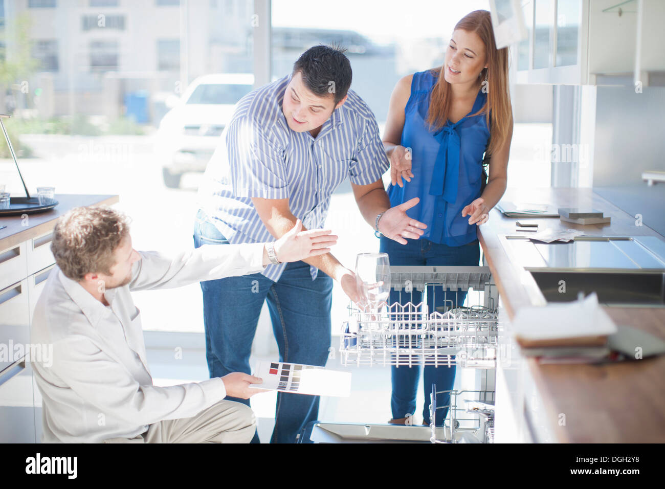 Couple and salesman looking at dishwasher in kitchen showroom Stock ...