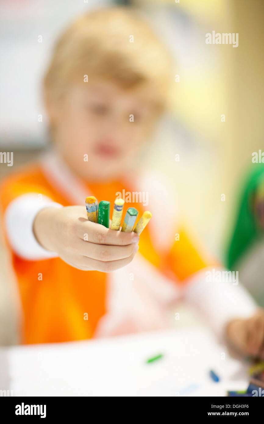 Boy holding out crayons Stock Photo - Alamy