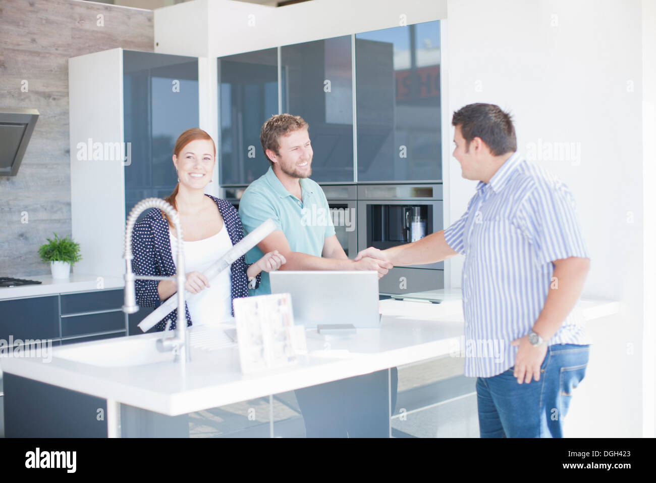 Young couple with salesman in kitchen showroom Stock Photo - Alamy