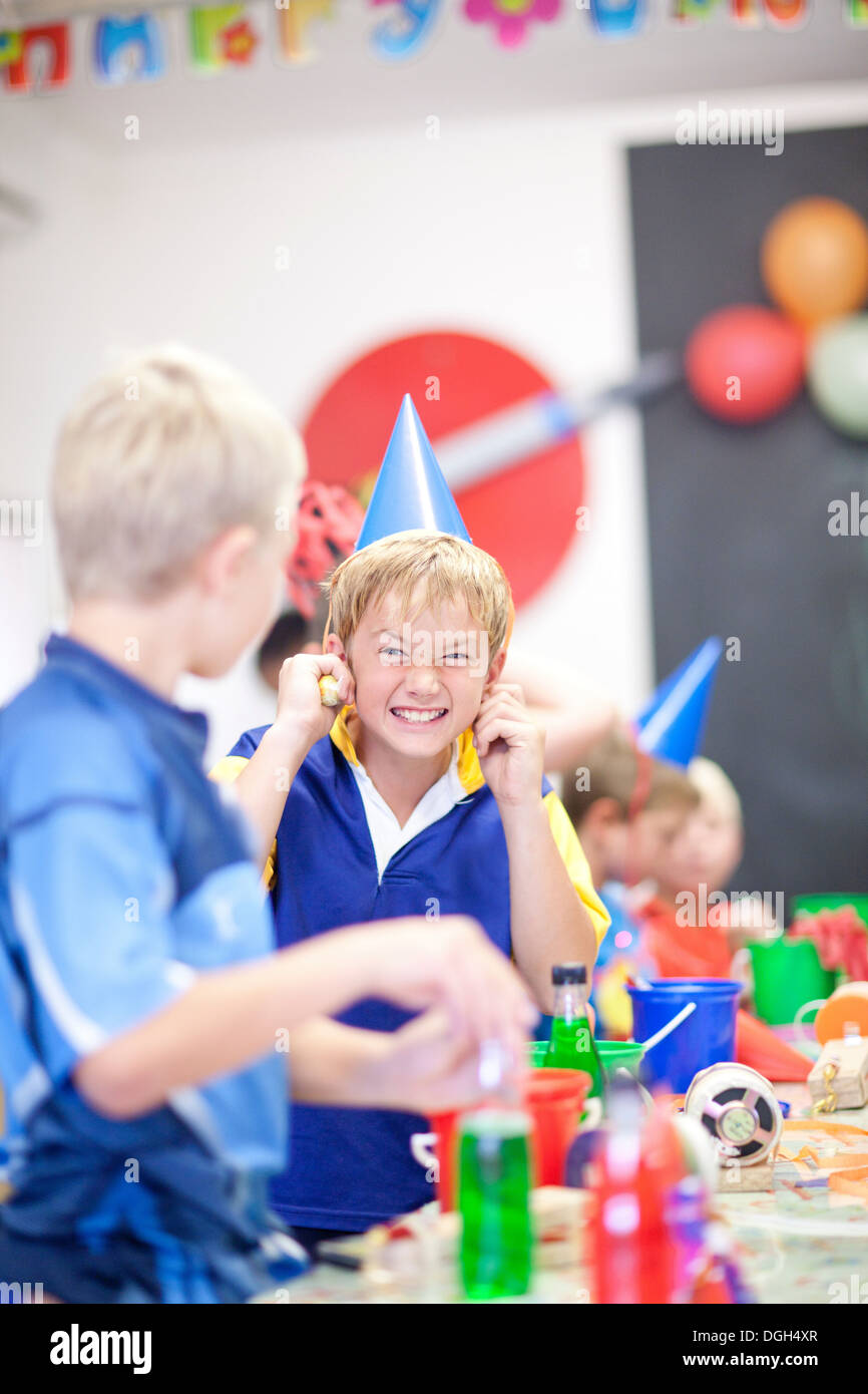 Boy at birthday party with fingers in ears Stock Photo - Alamy