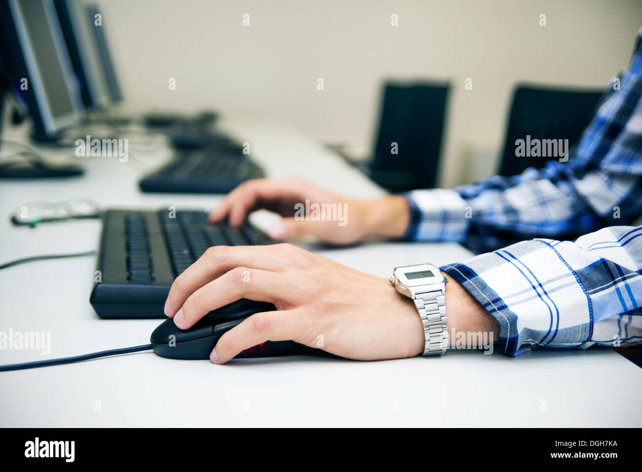 Young man typing on keyboard. Training room with computers Stock Photo ...