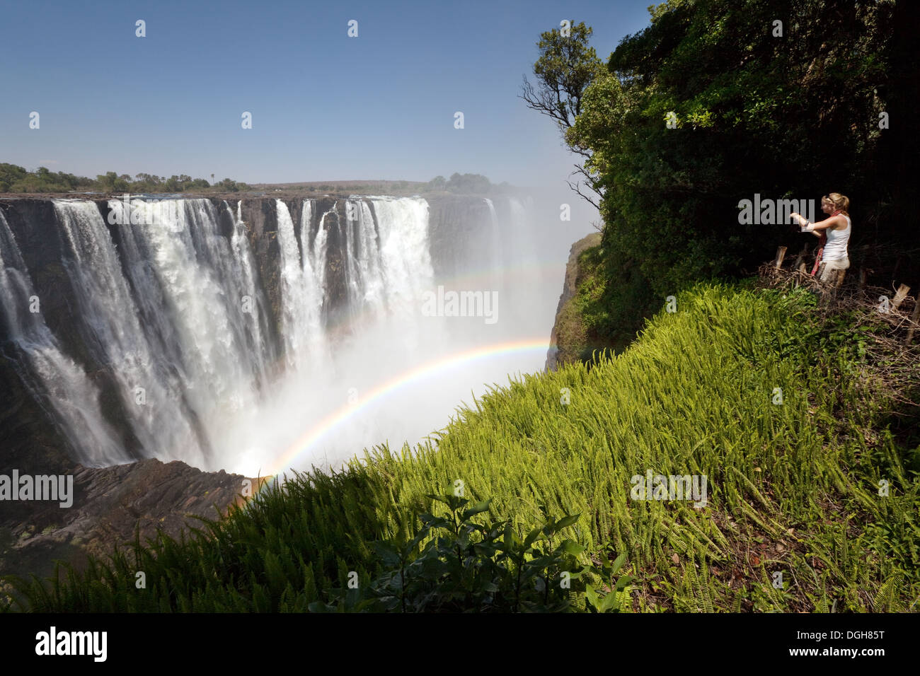 Victoria Falls tourist; a woman taking a photo of the Victoria Falls ...