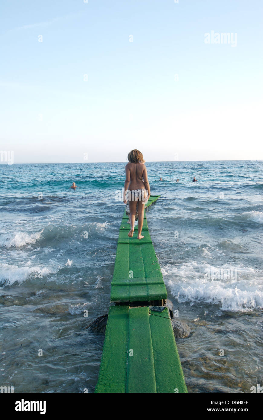 Young woman crossing popular wood catwalk in Sa Trinxa, Salinas beach ...