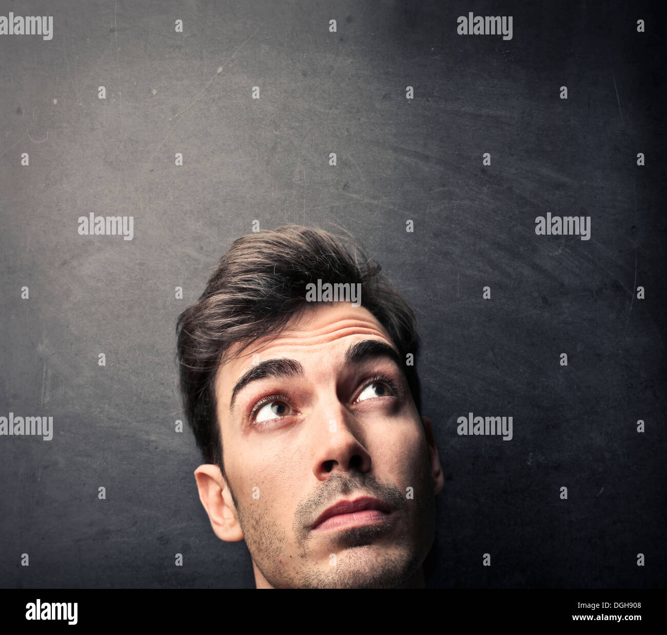 Guy thinking with a blackboard behind him Stock Photo - Alamy
