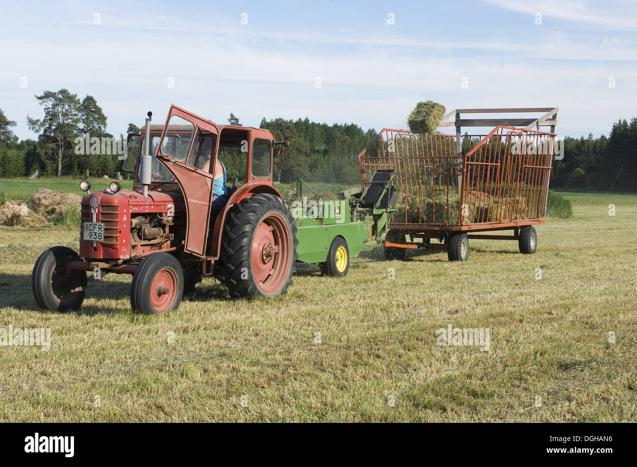 Tractor baling hay crop, baler tossing small bales into wagon, Sweden Stock Photo - Alamy