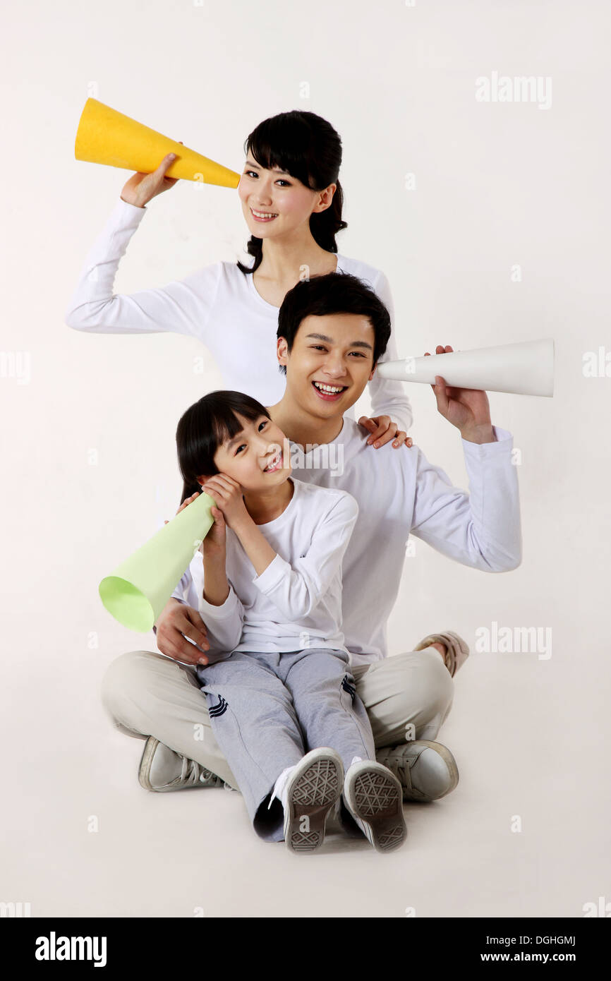 East Asian family with one child listening to the speakers, smiling and ...