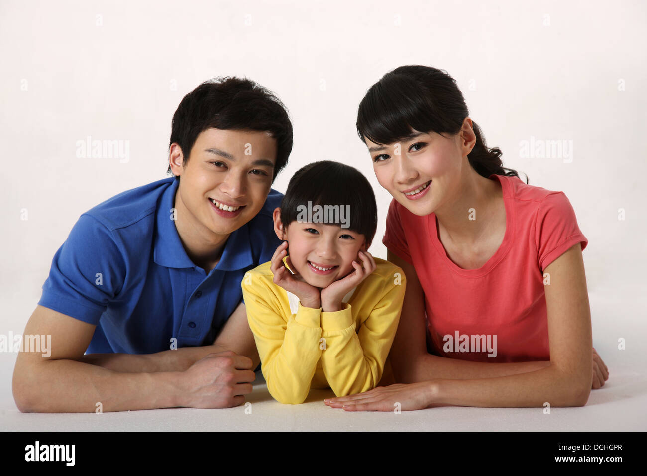 East Asian family with one child lying on the floor, daughter holding ...