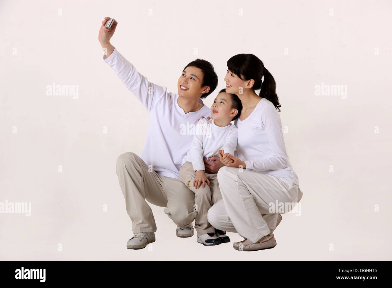 East Asian family with one child, embracing, crouching on the floor ...