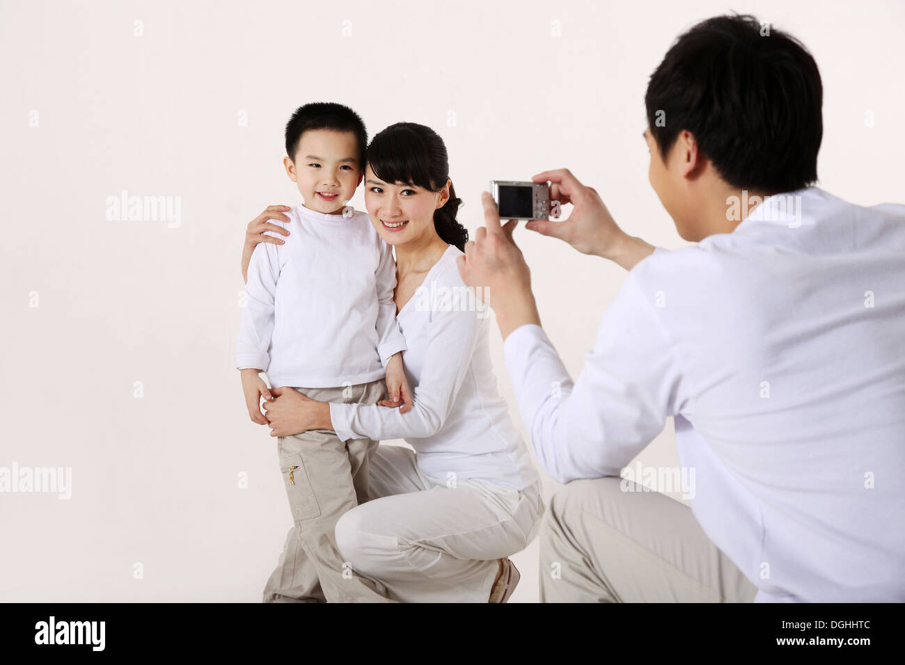 East Asian family with one child, embracing, crouching on the floor ...