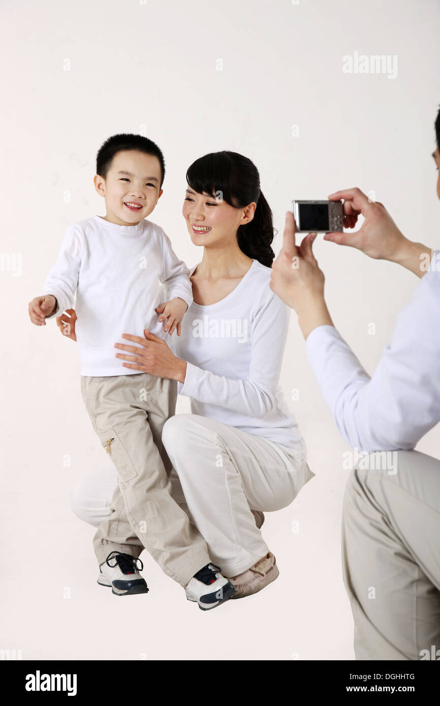 East Asian family with one child, embracing, crouching on the floor ...