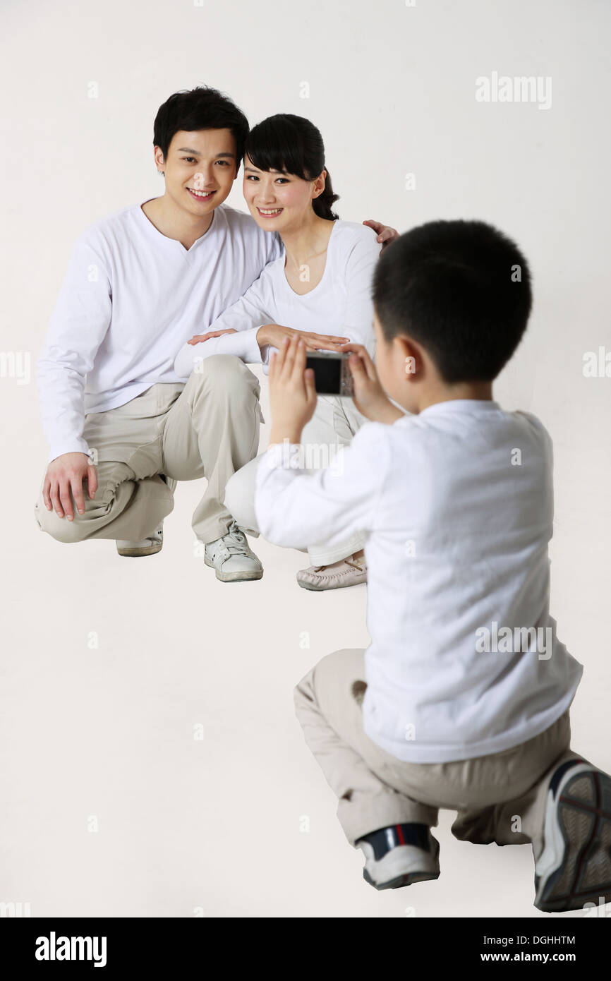 East Asian family with one child, embracing, crouching on the floor ...