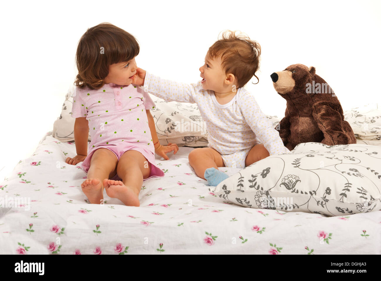 Happy baby boy touching toddler girl face in bed Stock Photo - Alamy
