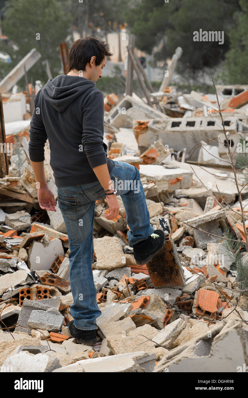 Lonely guy rummaging in lots of debris from a pulled down house Stock ...