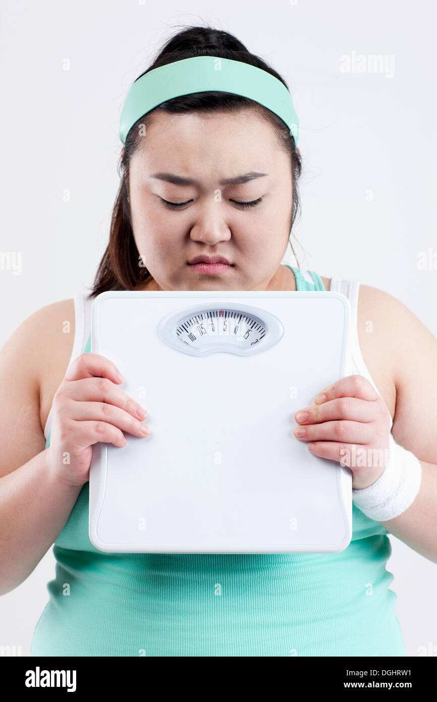 a fat girl in a gym outfit holding a weight scale Stock Photo - Alamy