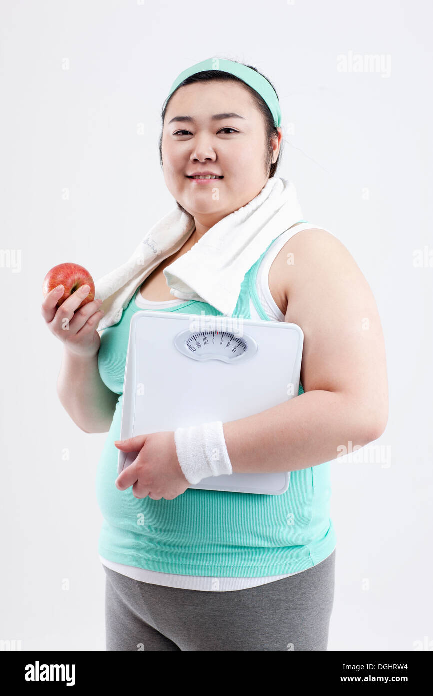 a fat girl in a gym outfit holding a weight scale Stock Photo - Alamy