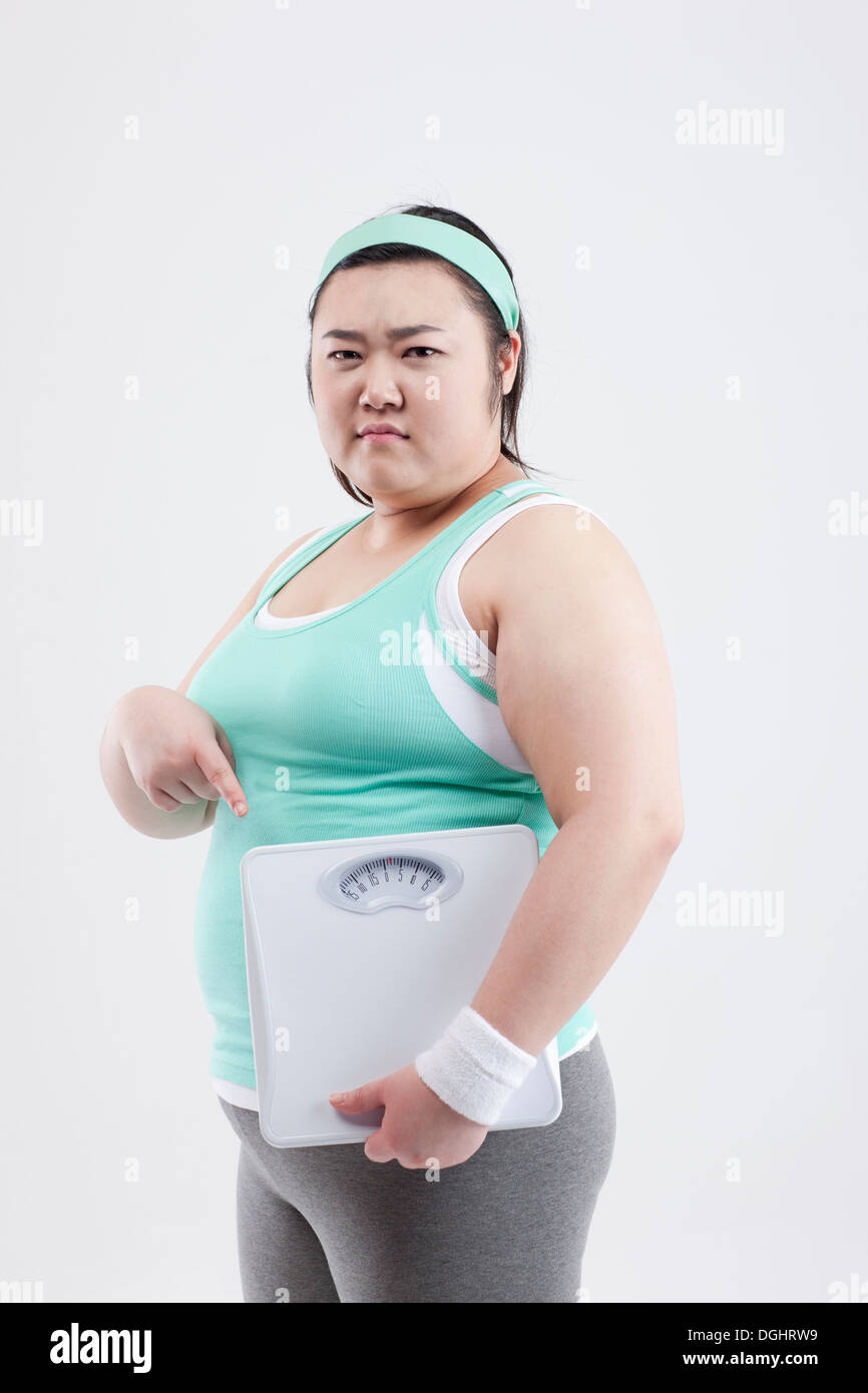a fat girl in a gym outfit holding a weight scale Stock Photo - Alamy