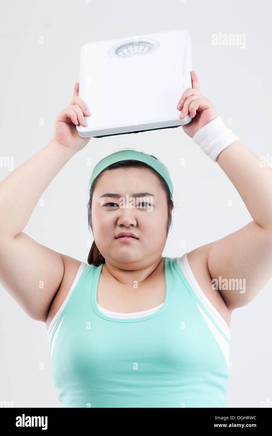 a fat girl in a gym outfit holding a weight scale Stock Photo - Alamy
