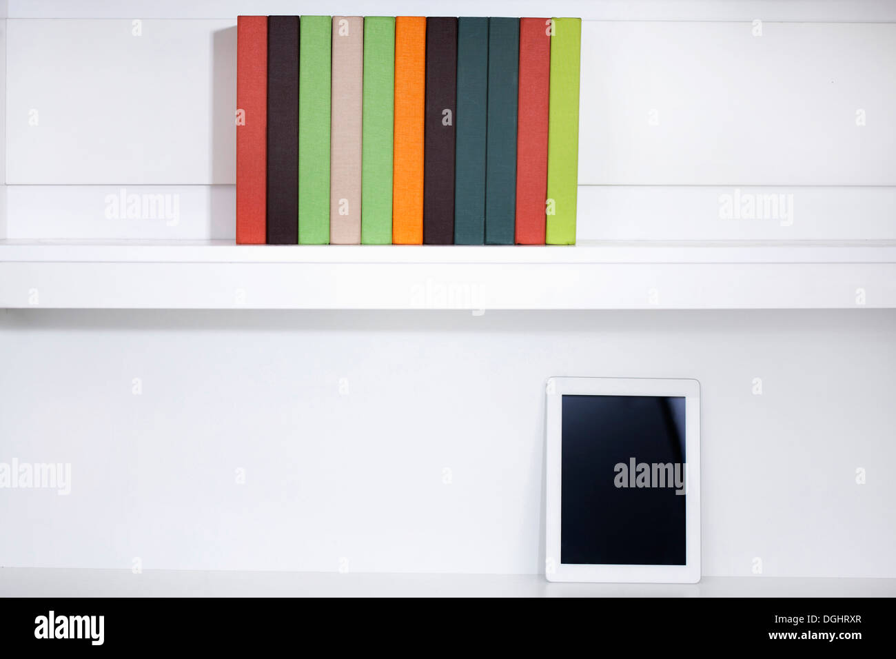 different color books in a row above a tablet Stock Photo - Alamy
