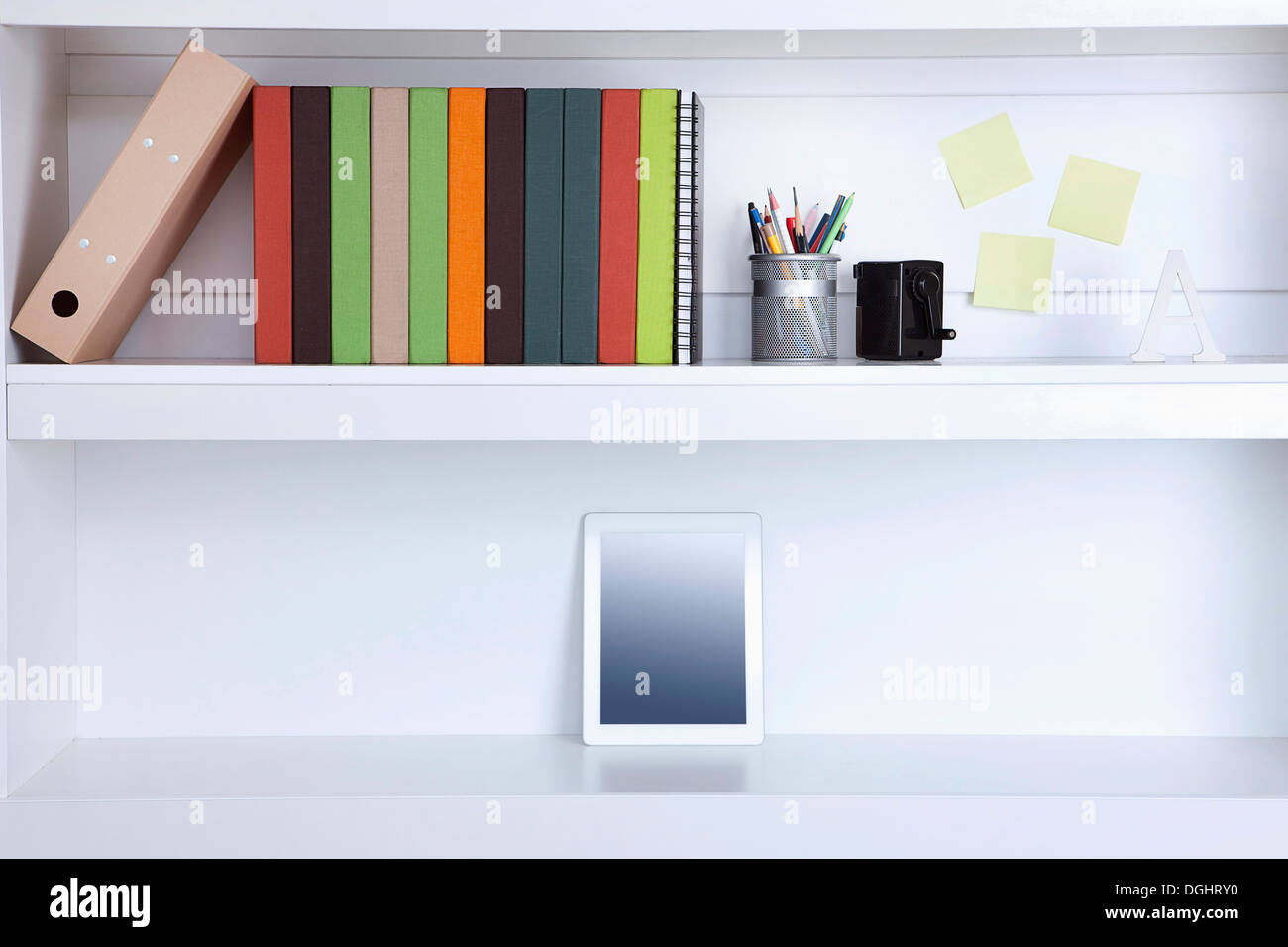 different color books in a row above a tablet Stock Photo - Alamy