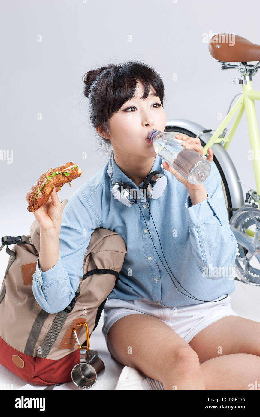 a woman sitting next to a bicycle eating Stock Photo - Alamy
