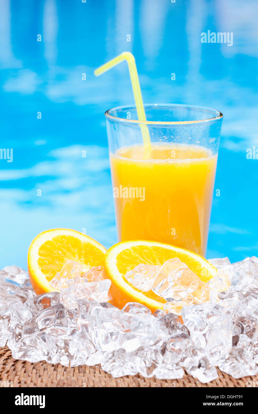 a glass of orange juice in ice next to a pool Stock Photo - Alamy