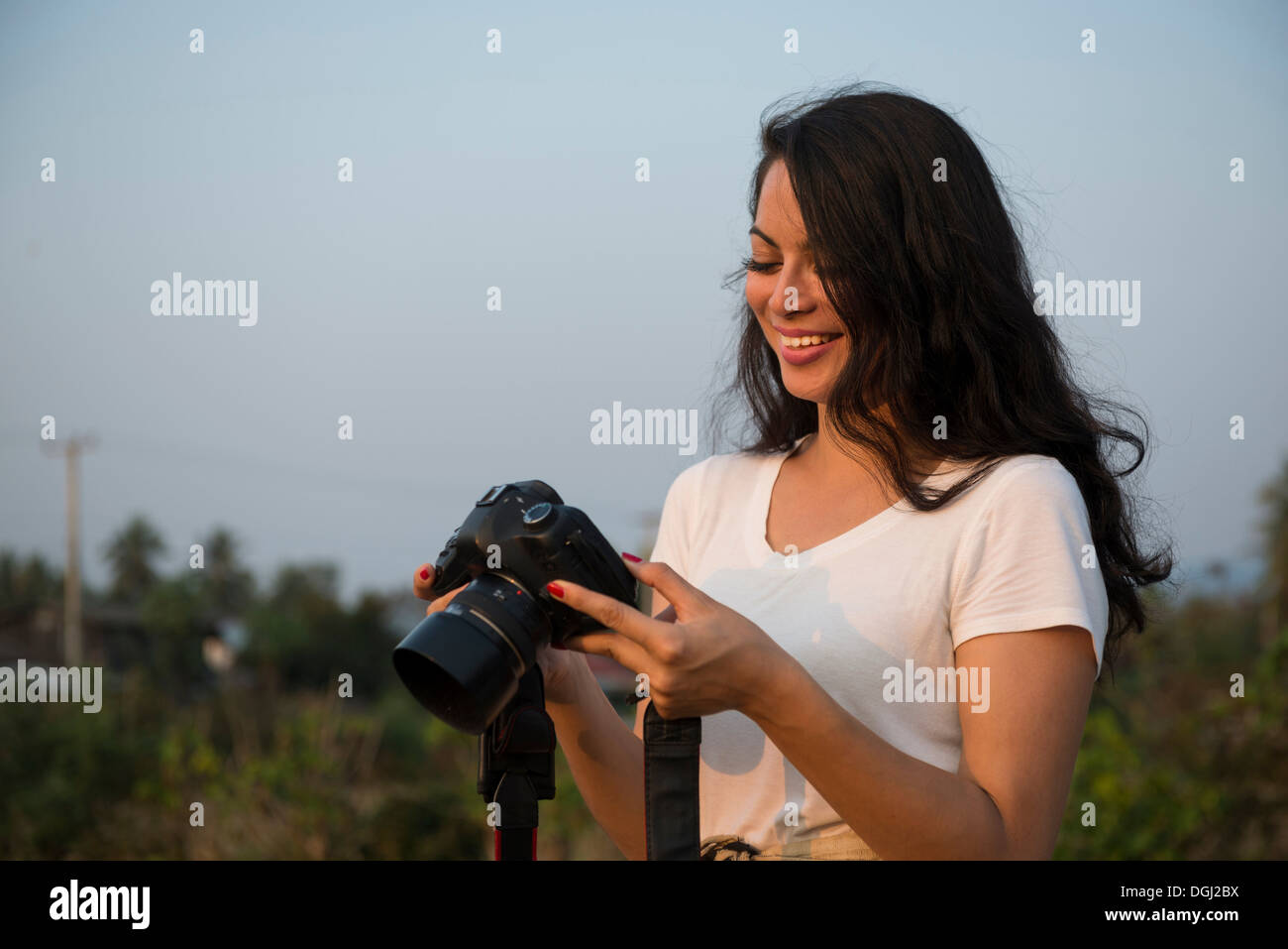 Woman with long black hair holding camera Stock Photo - Alamy