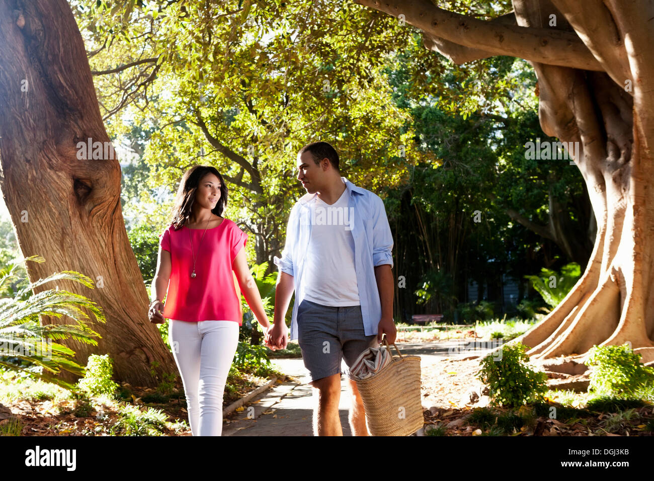 Young couple walking on path through trees Stock Photo - Alamy