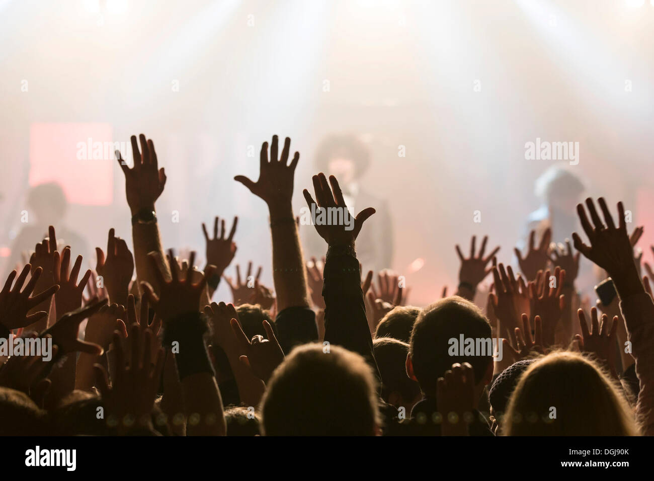 Concertgoers stretching their hands in the air at the concert of the ...
