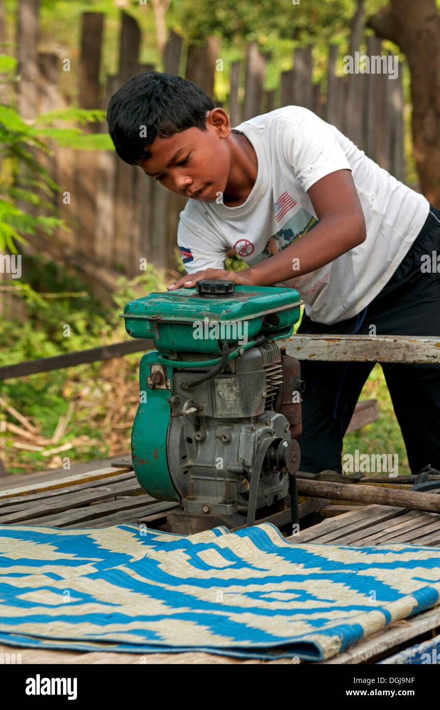 A young Khmer starting the engine of the bamboo train, a motorized ...