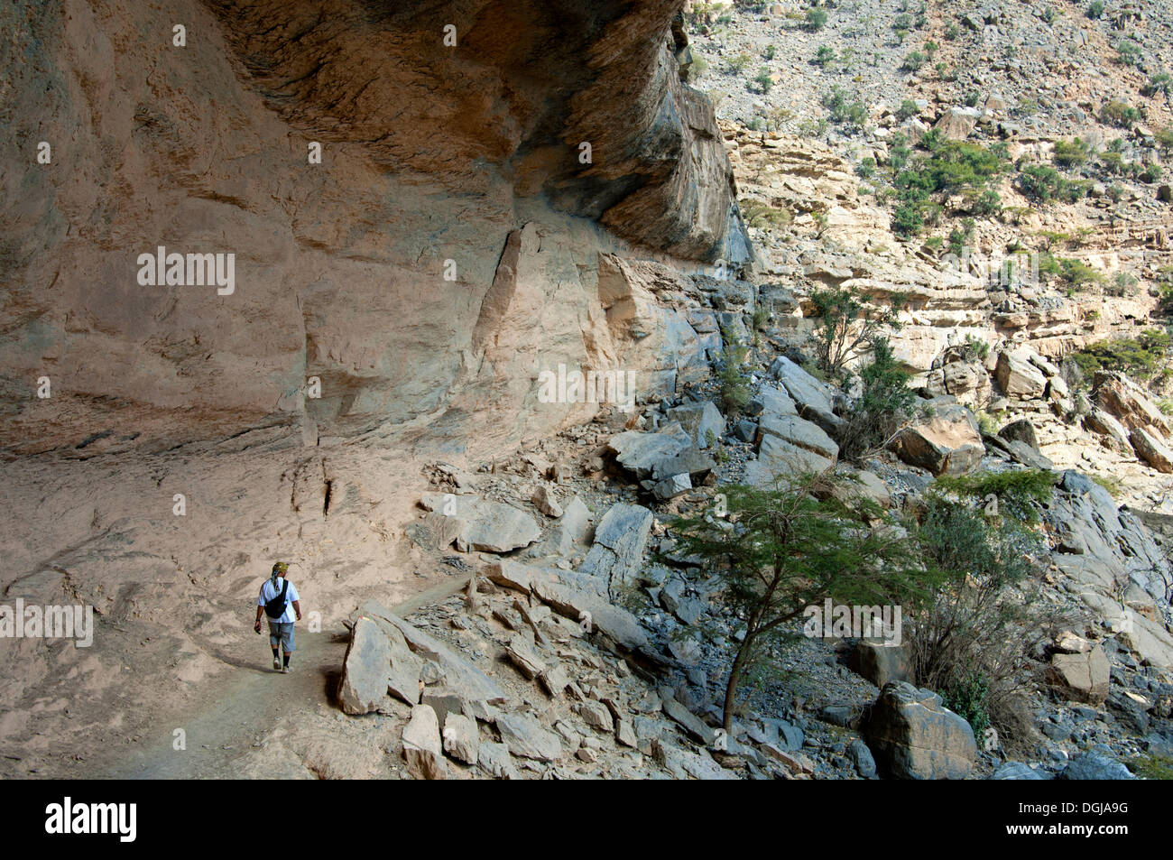 Local hiker walking under a rock overhang on the path to the abandoned ...