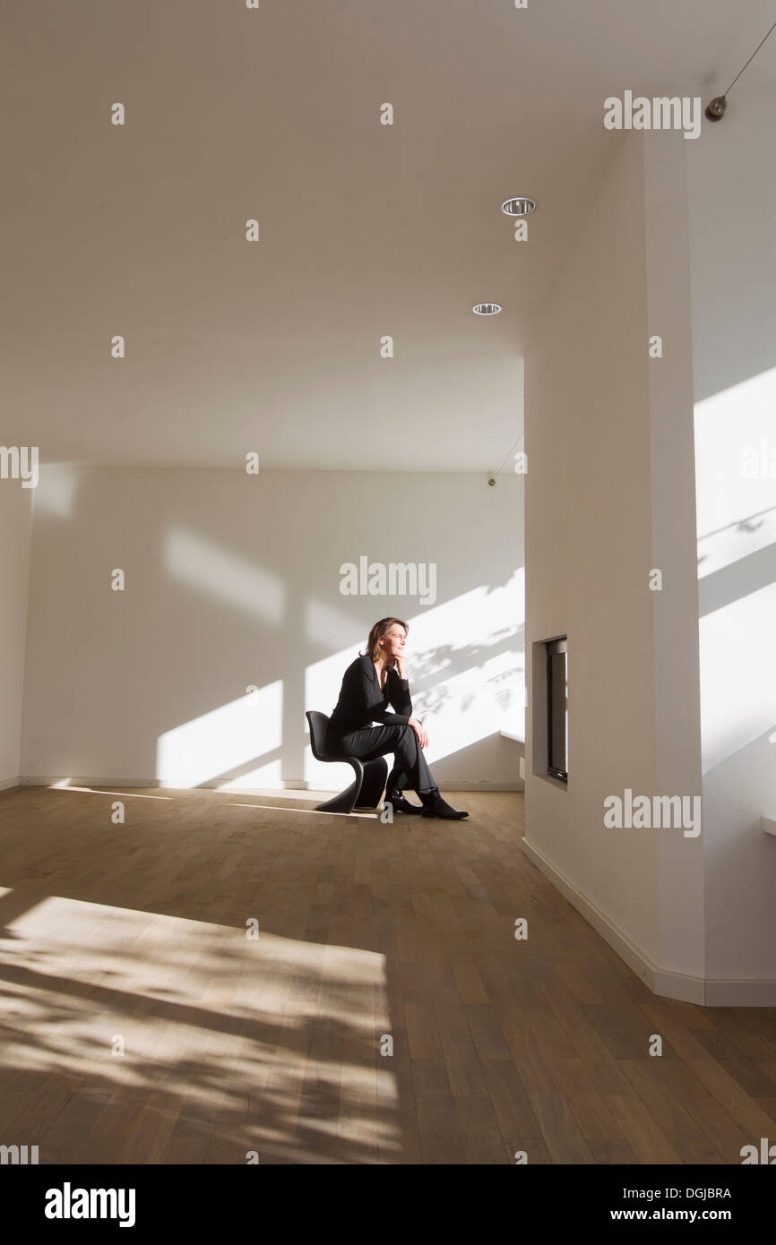 Woman sitting on chair in empty room Stock Photo - Alamy