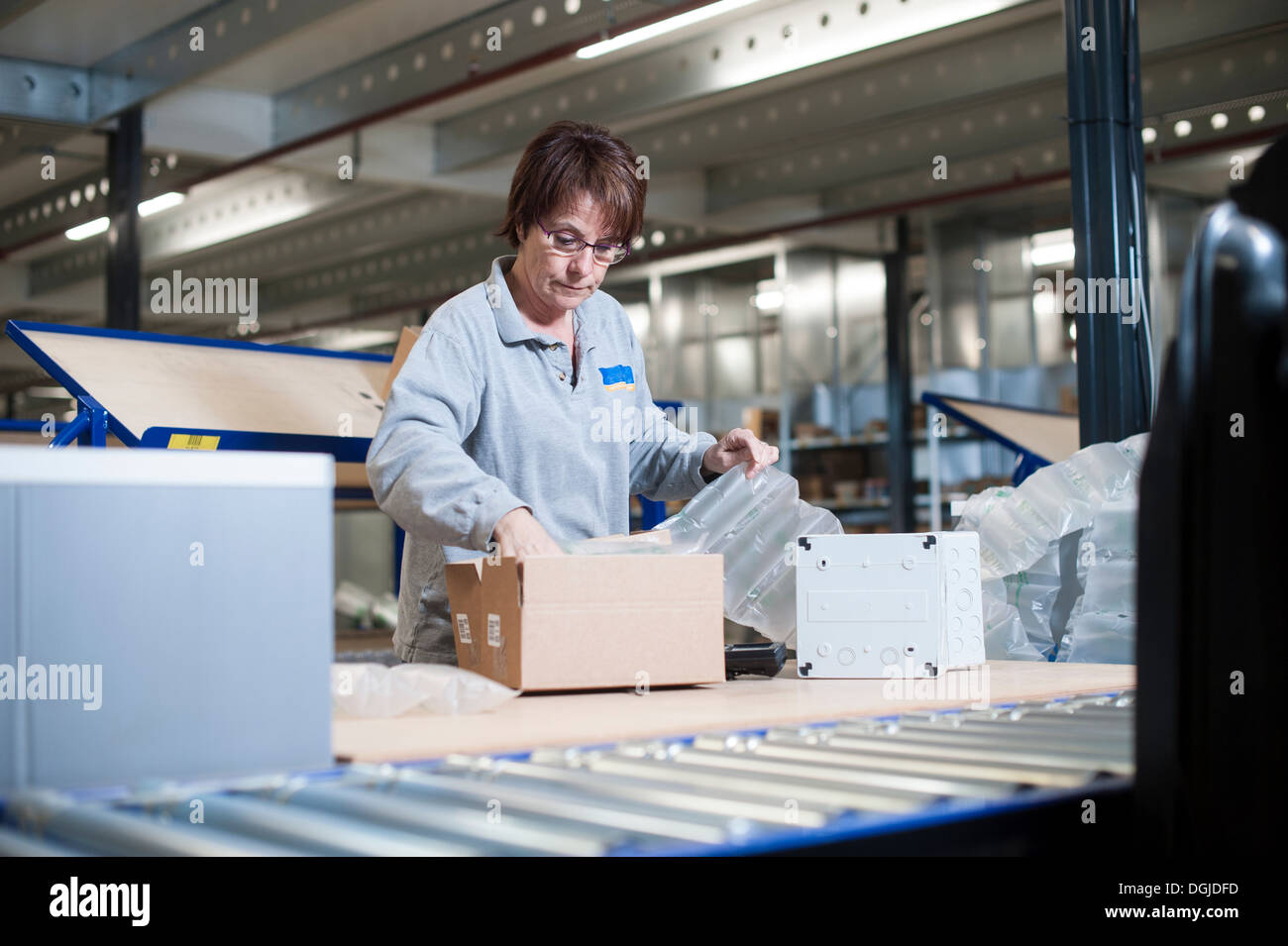 Female warehouse worker packing box for conveyor belt Stock Photo - Alamy