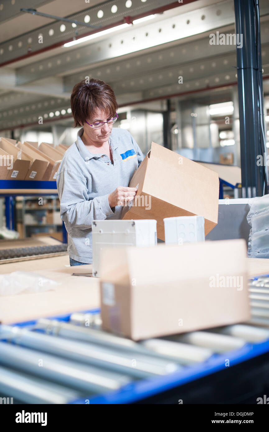 Female warehouse worker labeling box for conveyor belt Stock Photo - Alamy