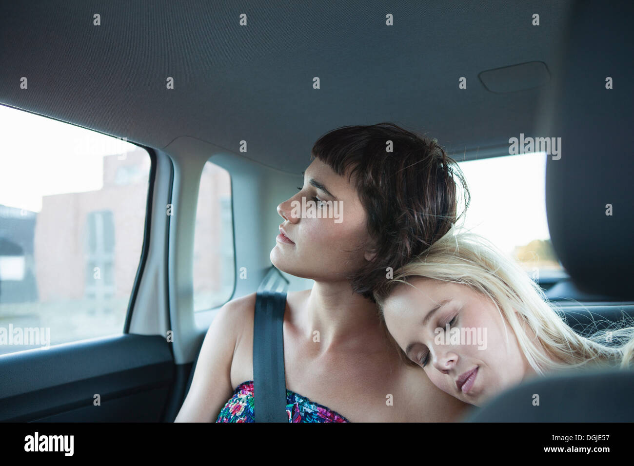 Women in backseat of car, one with head on friend's shoulder Stock ...