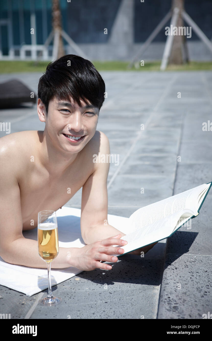 a man reading a book next to the pool Stock Photo - Alamy