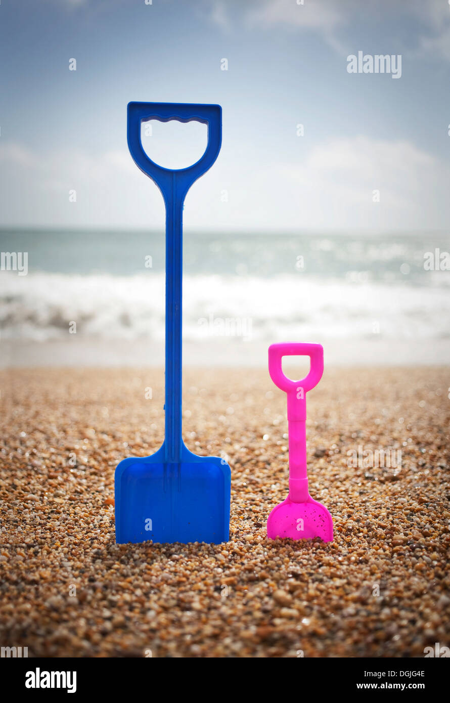 Blue and pink spades standing in sand at beach Stock Photo - Alamy