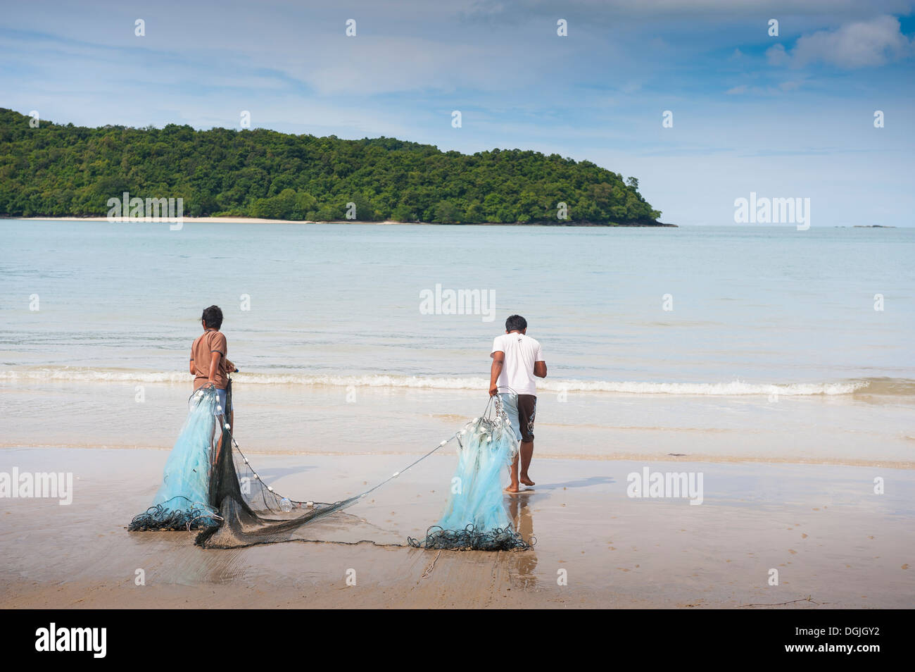 Two Malaysian fishermen dragging a fishing net across Pantai Tengah ...