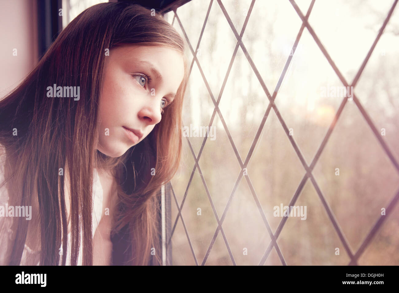 Young girl looking though window Stock Photo - Alamy